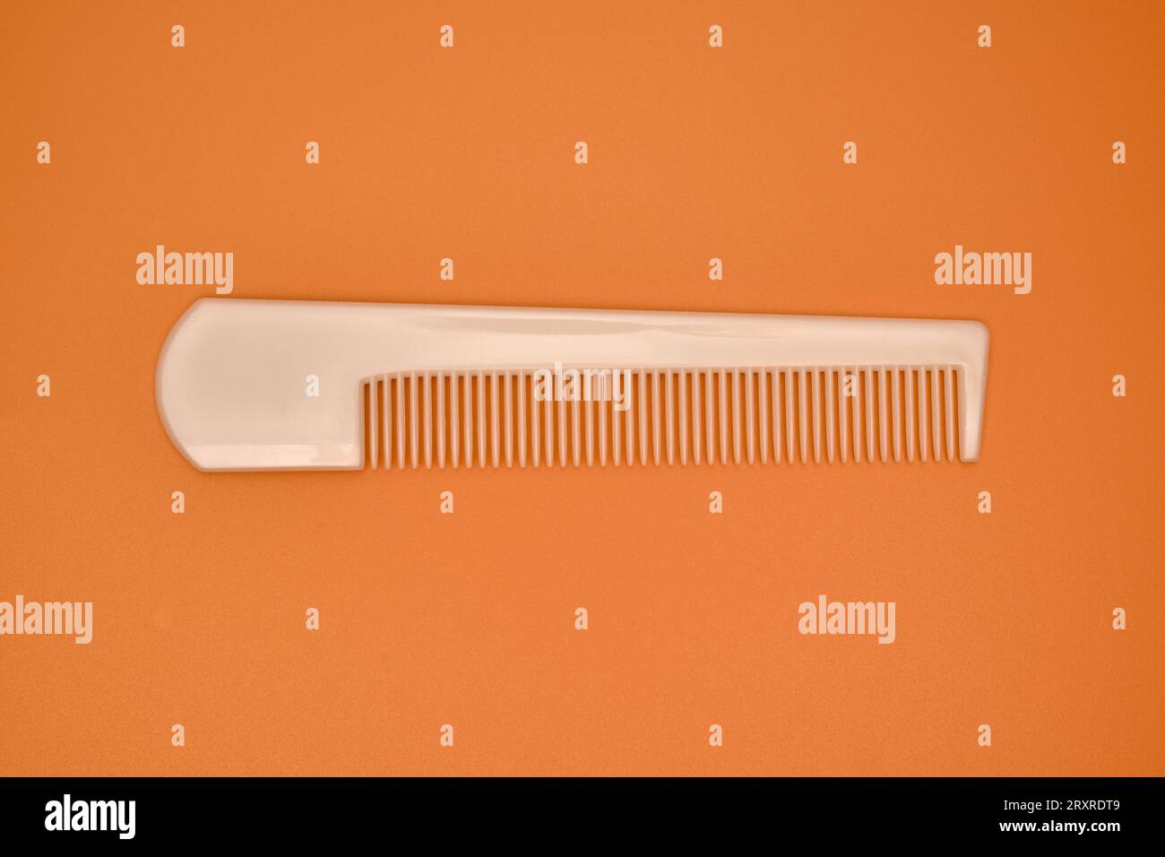 One ivory plastic comb on an orange background Stock Photo - Alamy