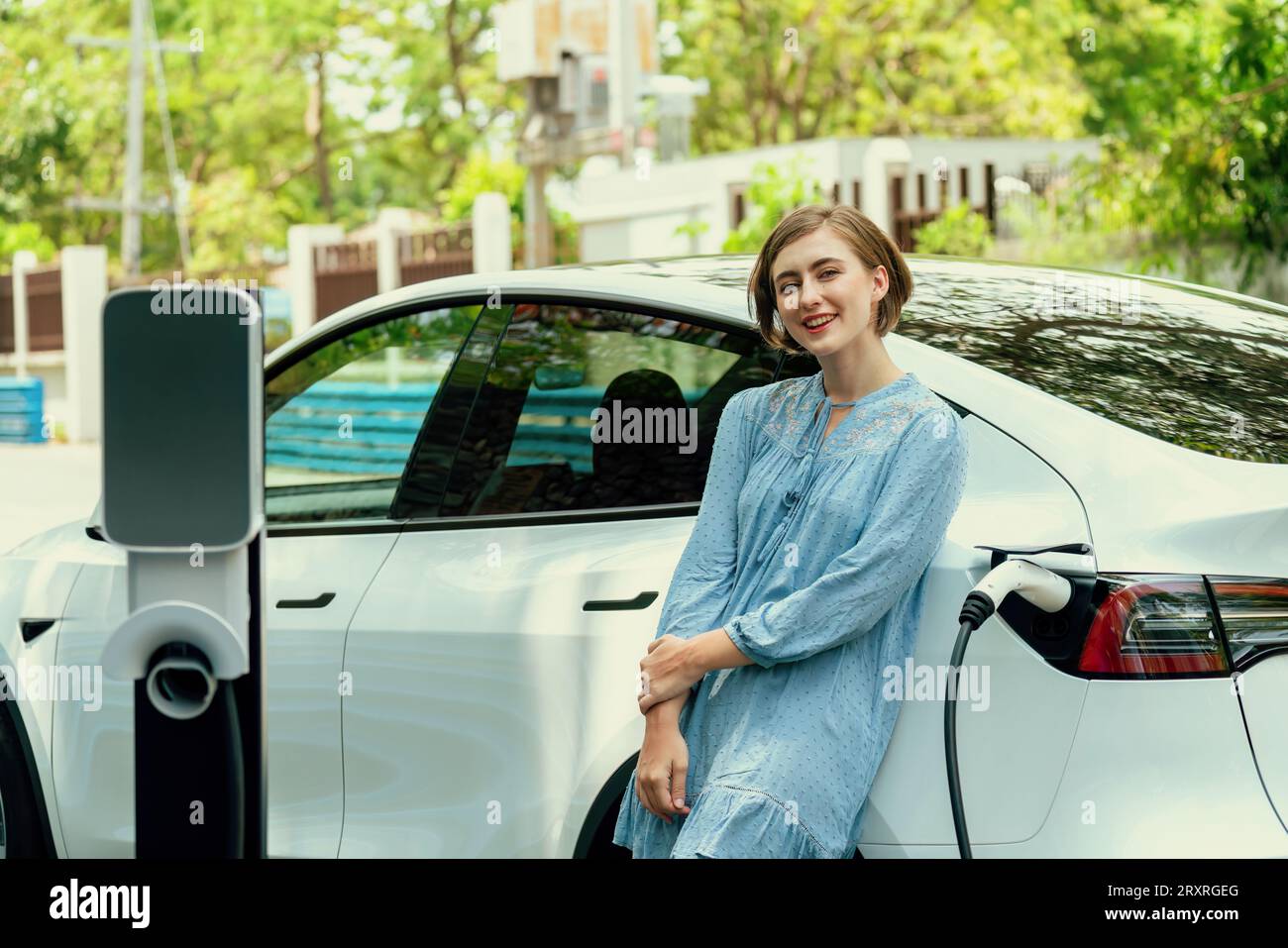 Beautiful young woman recharging her electric car from home EV charging ...