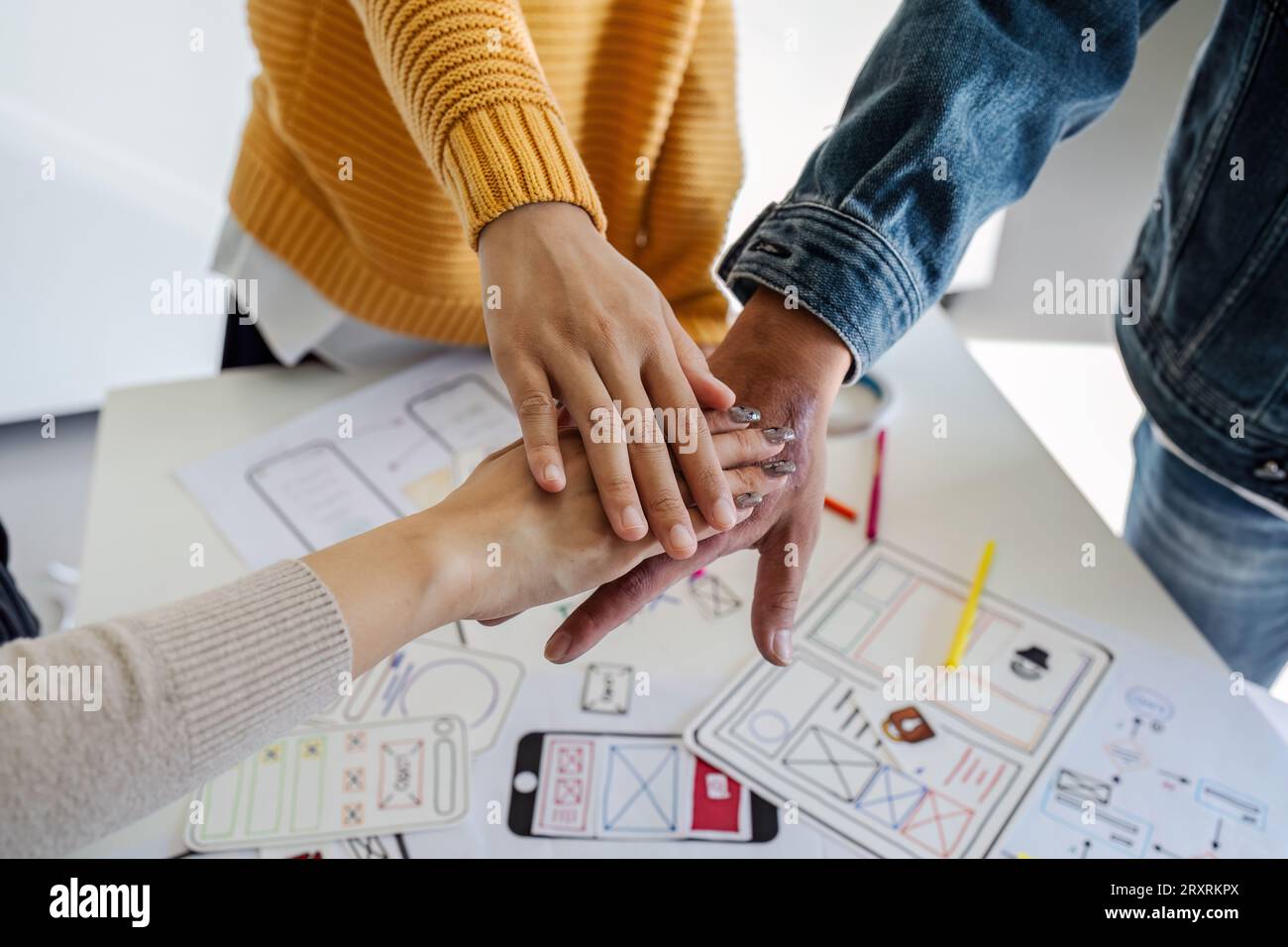 Asian ux developer and ui designer team stacking hands together ...