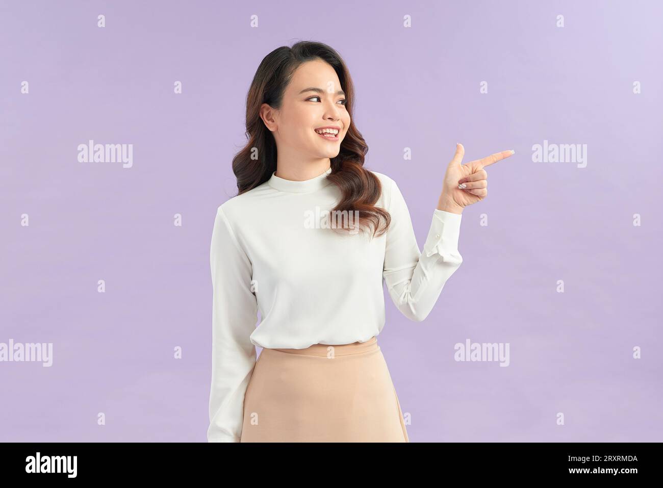 Asian young woman standing makes gesture fingers point upwards above ...