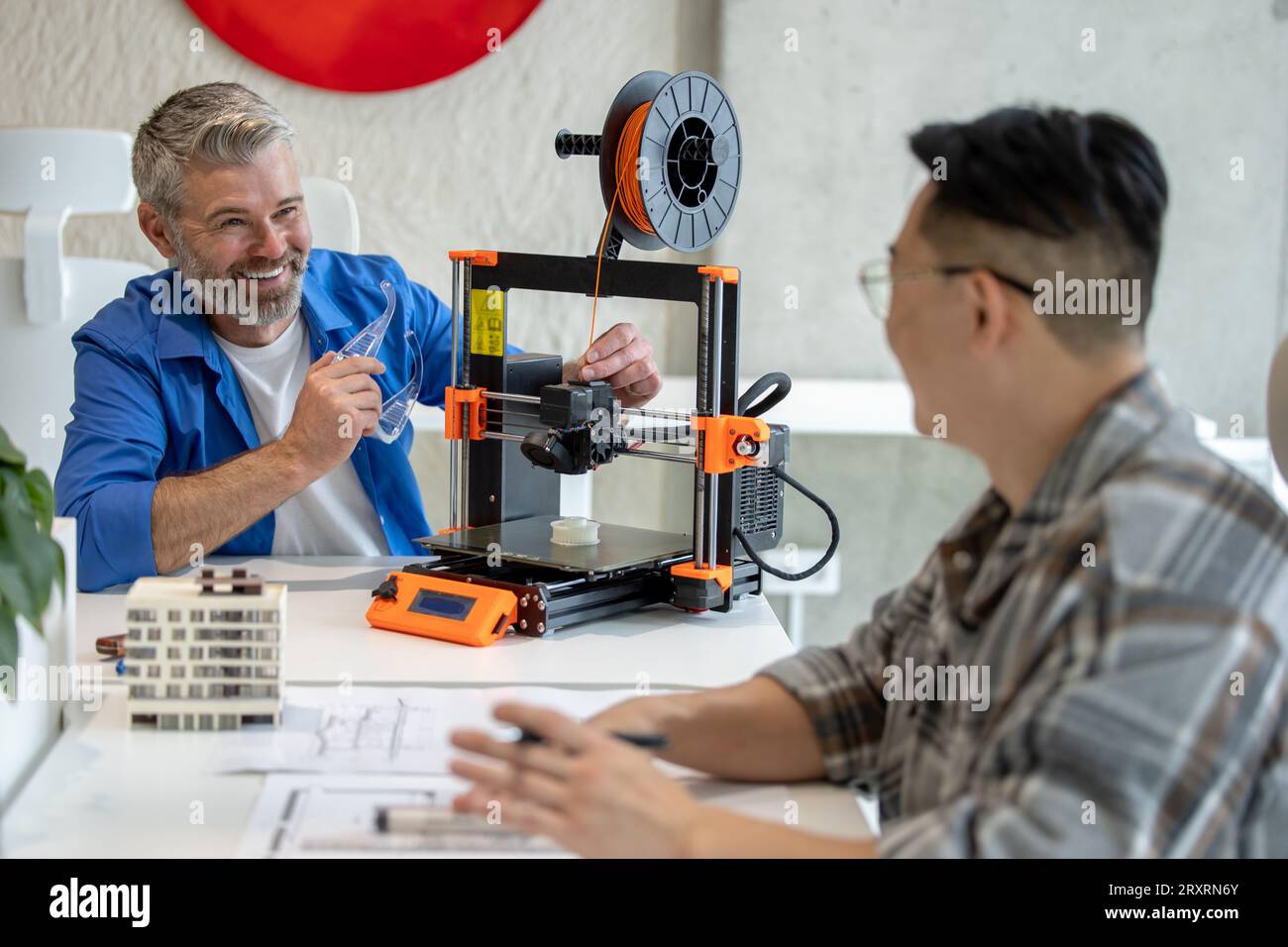 Architects working with 3D printer and projecting house model, drawing ...