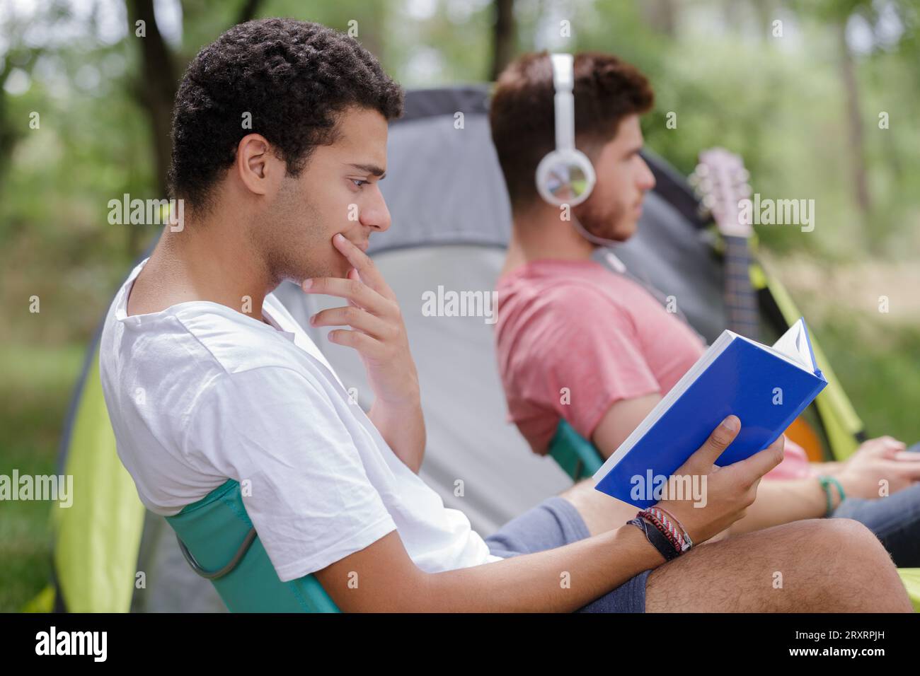 man reading a magazine while camping Stock Photo - Alamy