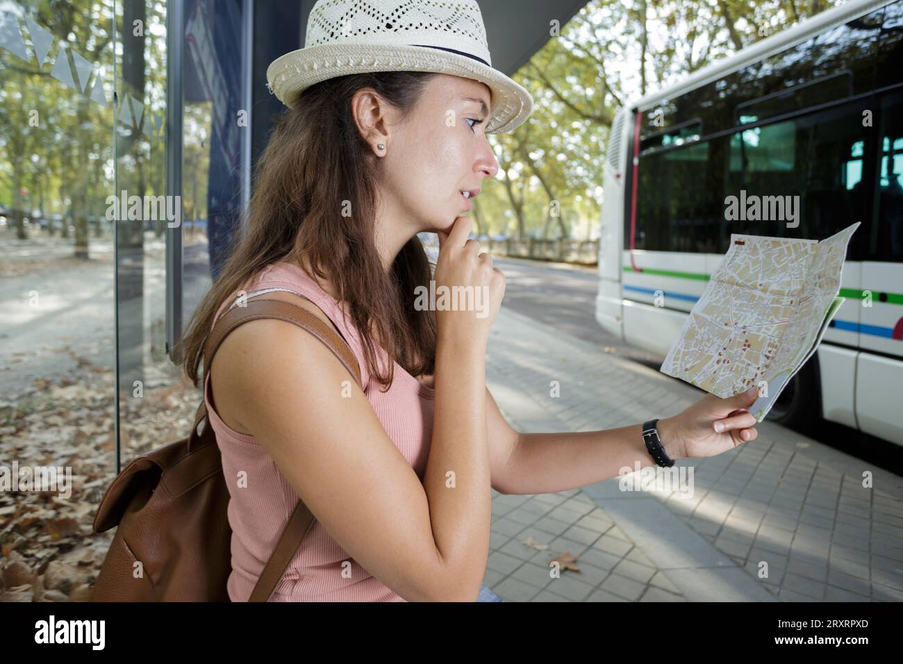 woman reading a map while waiting at bus stop Stock Photo - Alamy