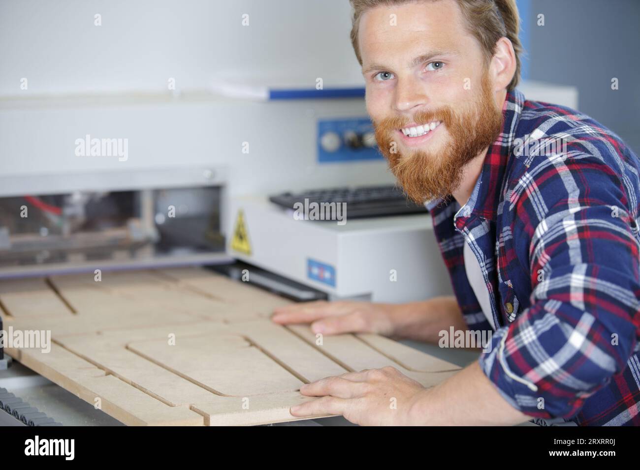 woodworker guiding wood into industrial machine Stock Photo - Alamy