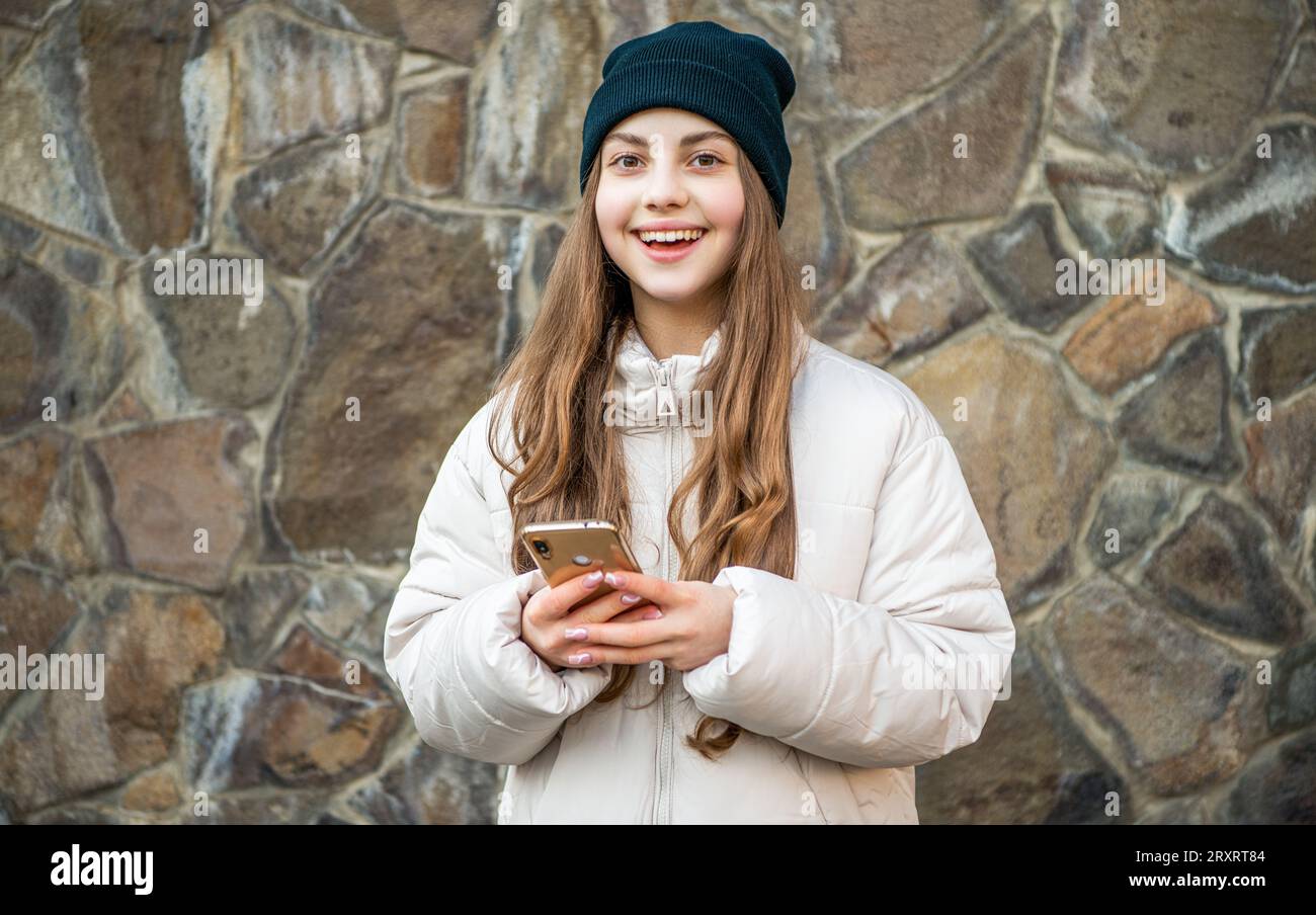 smiling teen girl texting on phone at stone background. teen girl ...