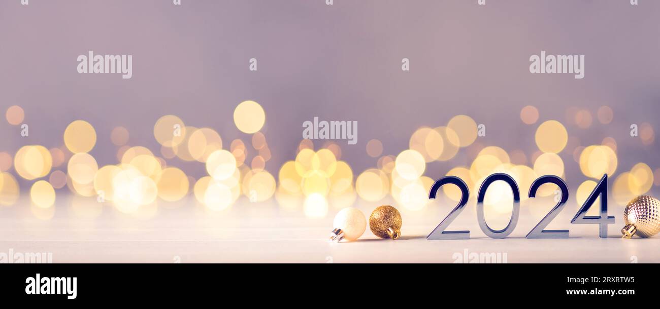 Metal numbers 2024 on a white table with Christmas decorations and bokeh lights. Happy New Year ...
