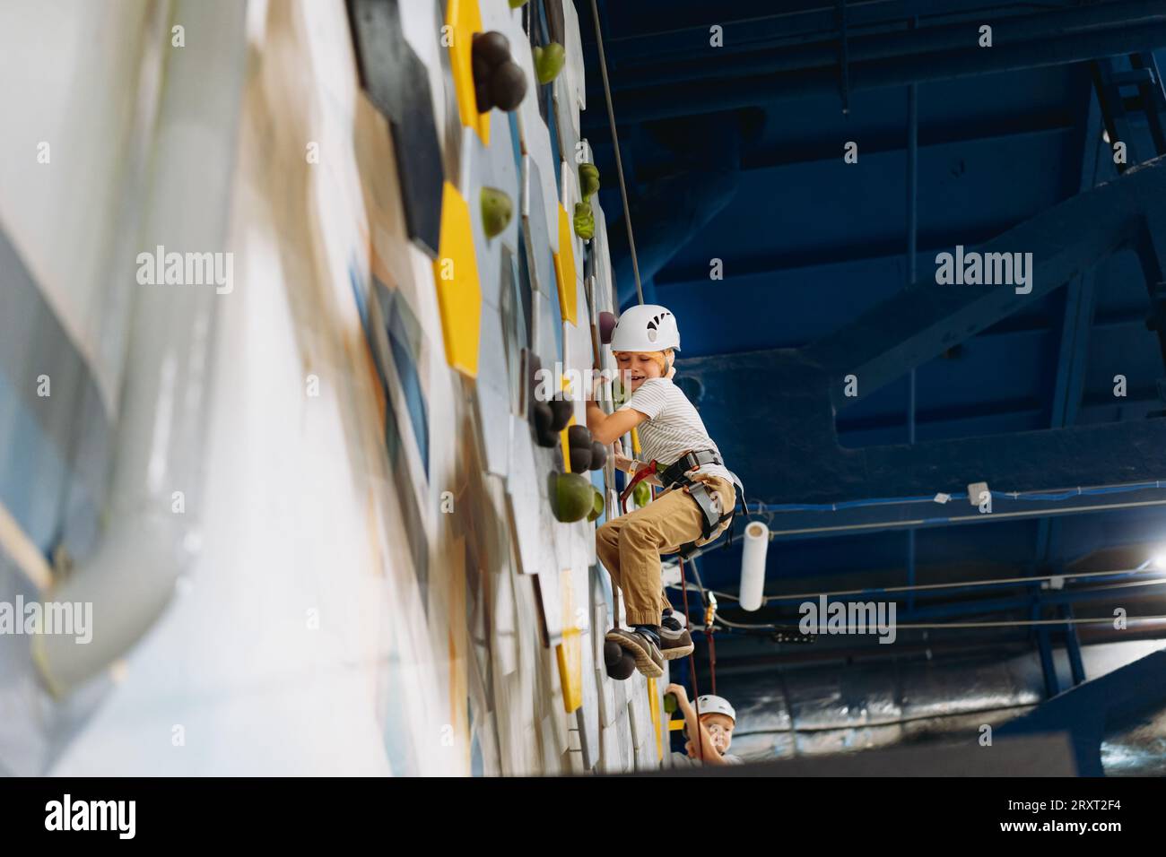 scared little boy climbing up the wall in adventure park passing ...