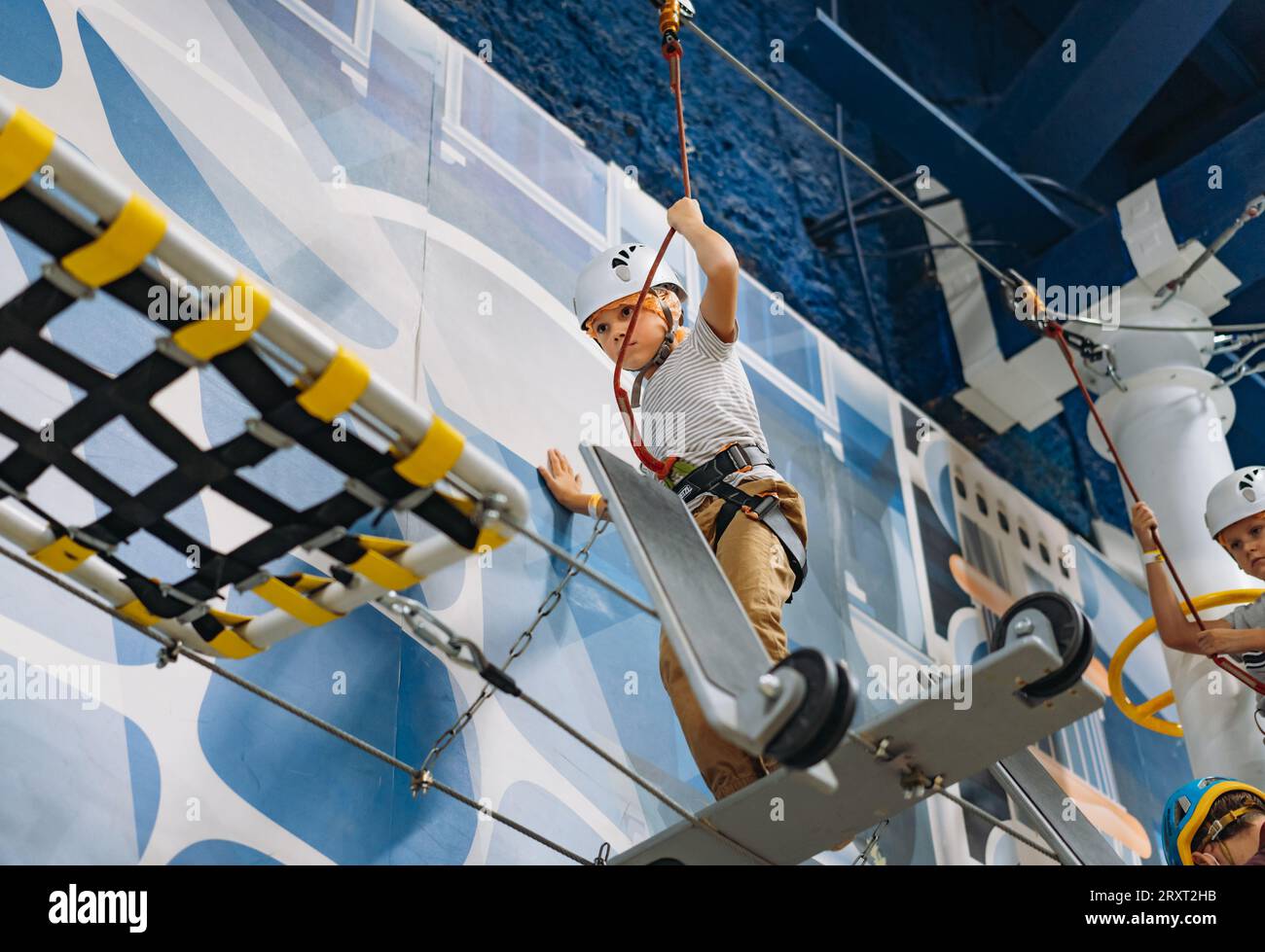 cute little boy climbing in adventure park passing obstacle course ...