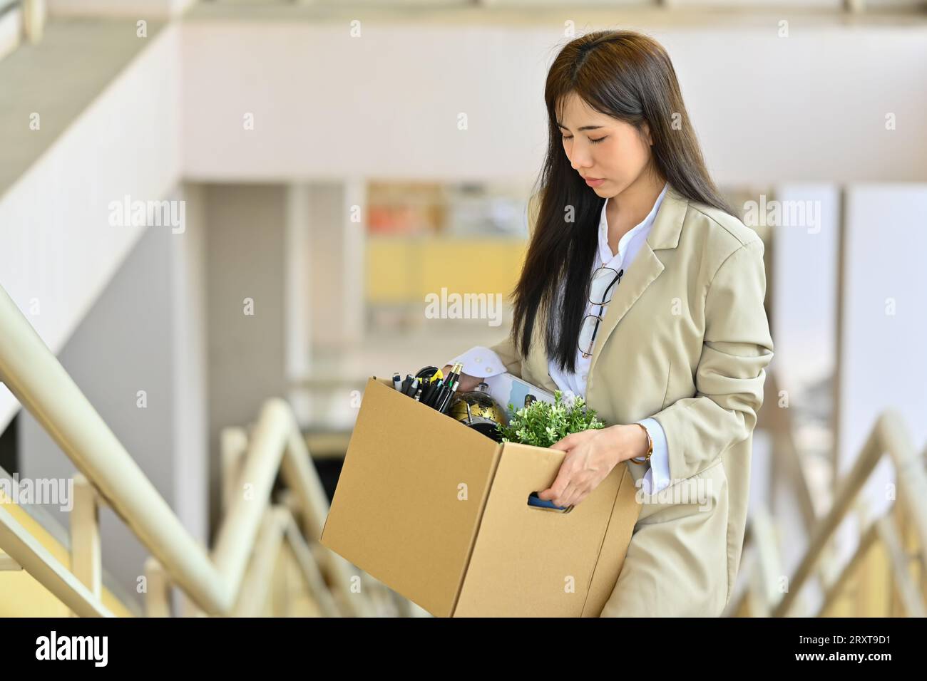 Sad fired female office worker holding cardboard box with belongings ...