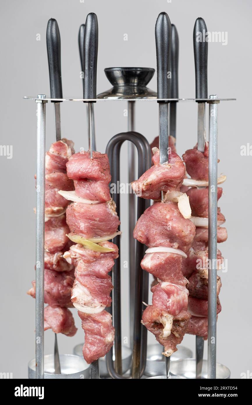 Cooking pork meat in an electric kebab maker on vertical skewers Stock ...