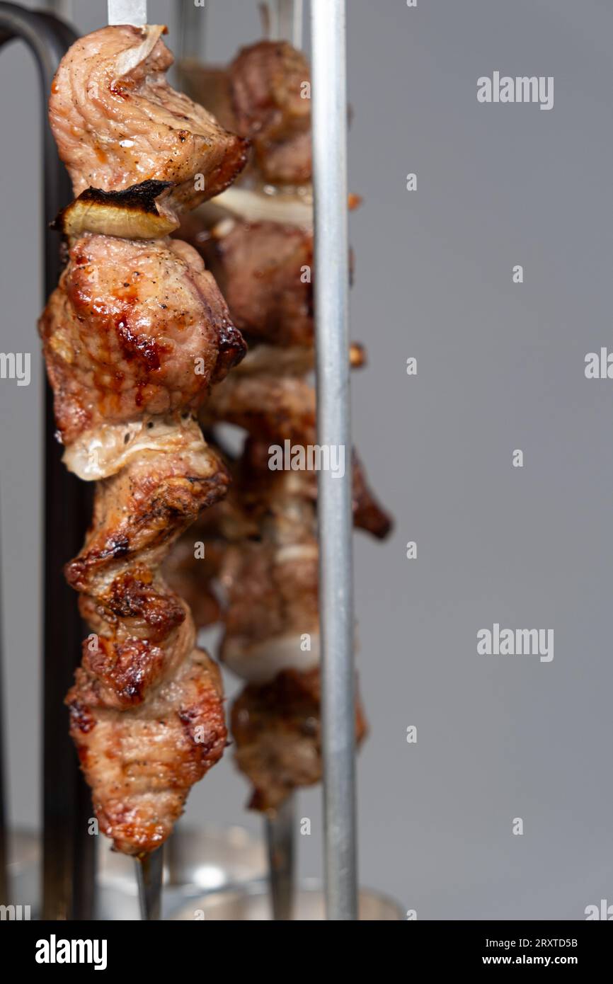 Cooking pork meat in an electric kebab maker on vertical skewers Stock ...