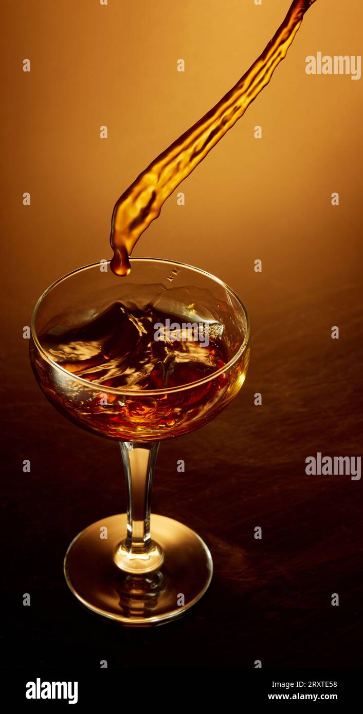 Top view photo of pouring whiskey, rum, brandy or gin to high glass ...