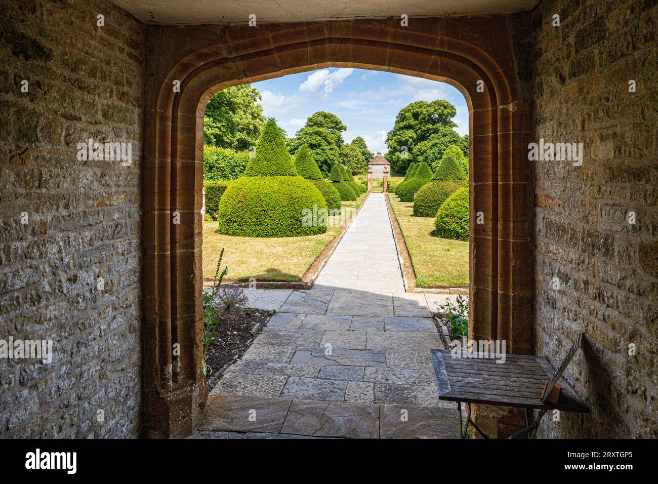 Yew topiary in the Arts and Crafts style garden viewed through a four ...