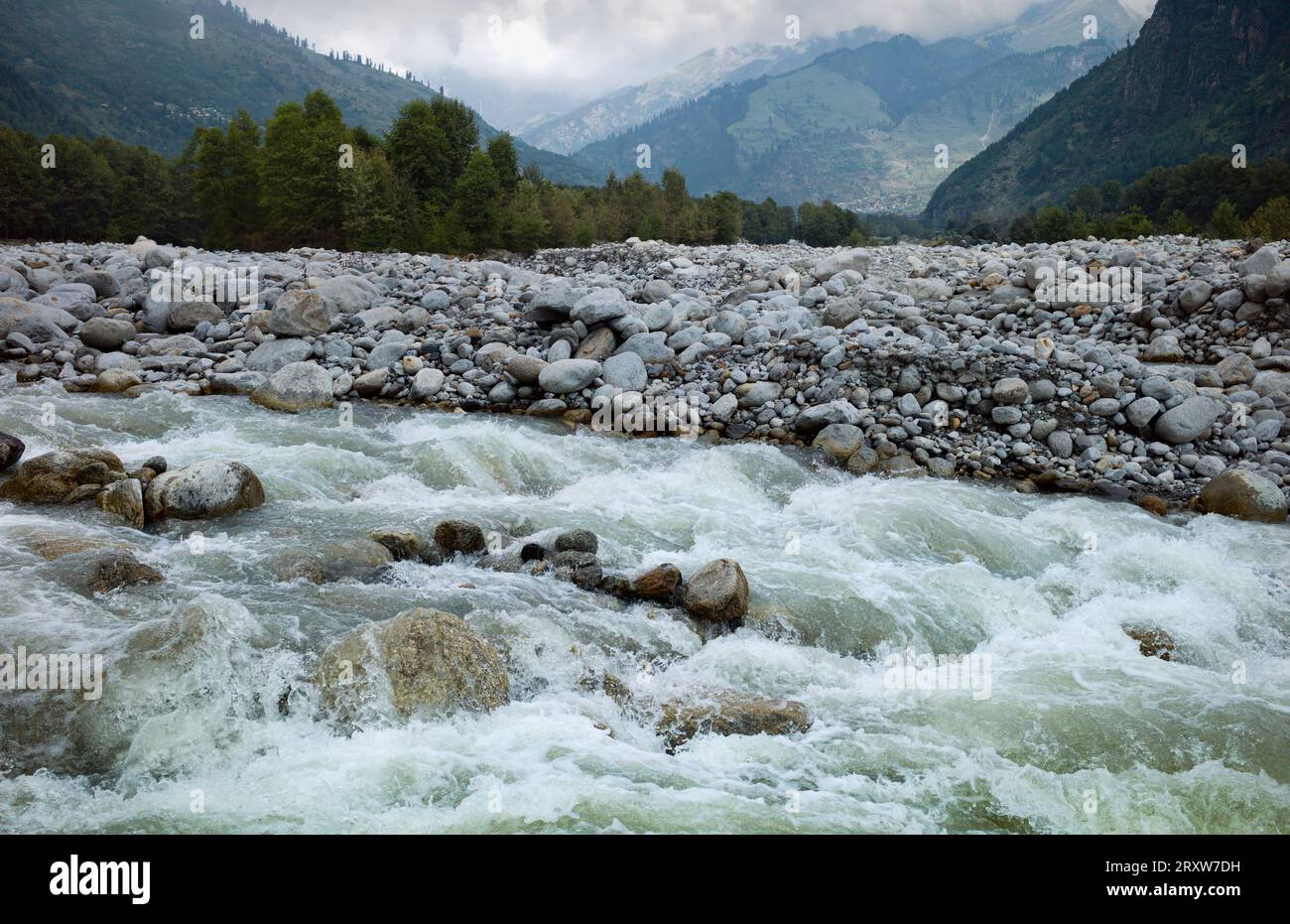 River flows through valley flanked by boulders and Himalayas with view ...
