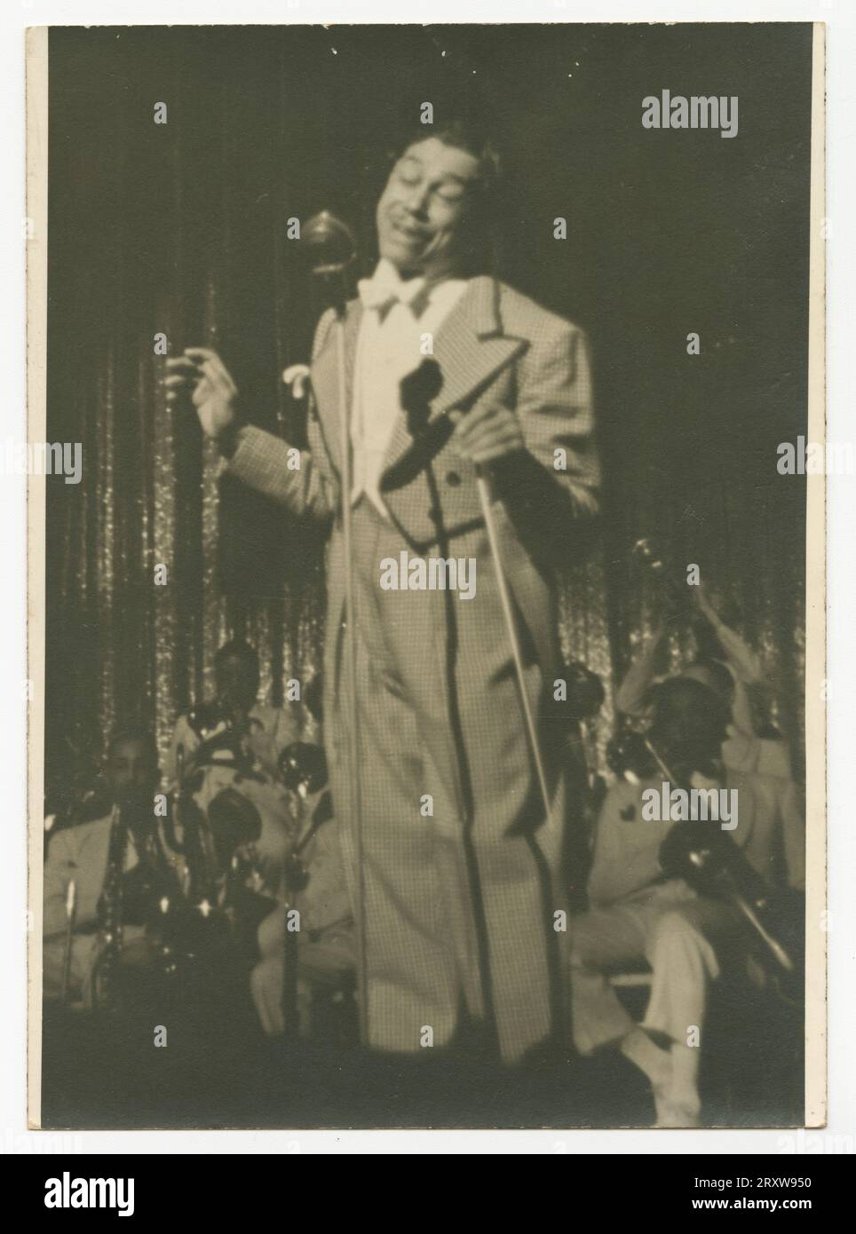 B & W photograph of Cab Calloway in a grey tuxedo singing in to the ...