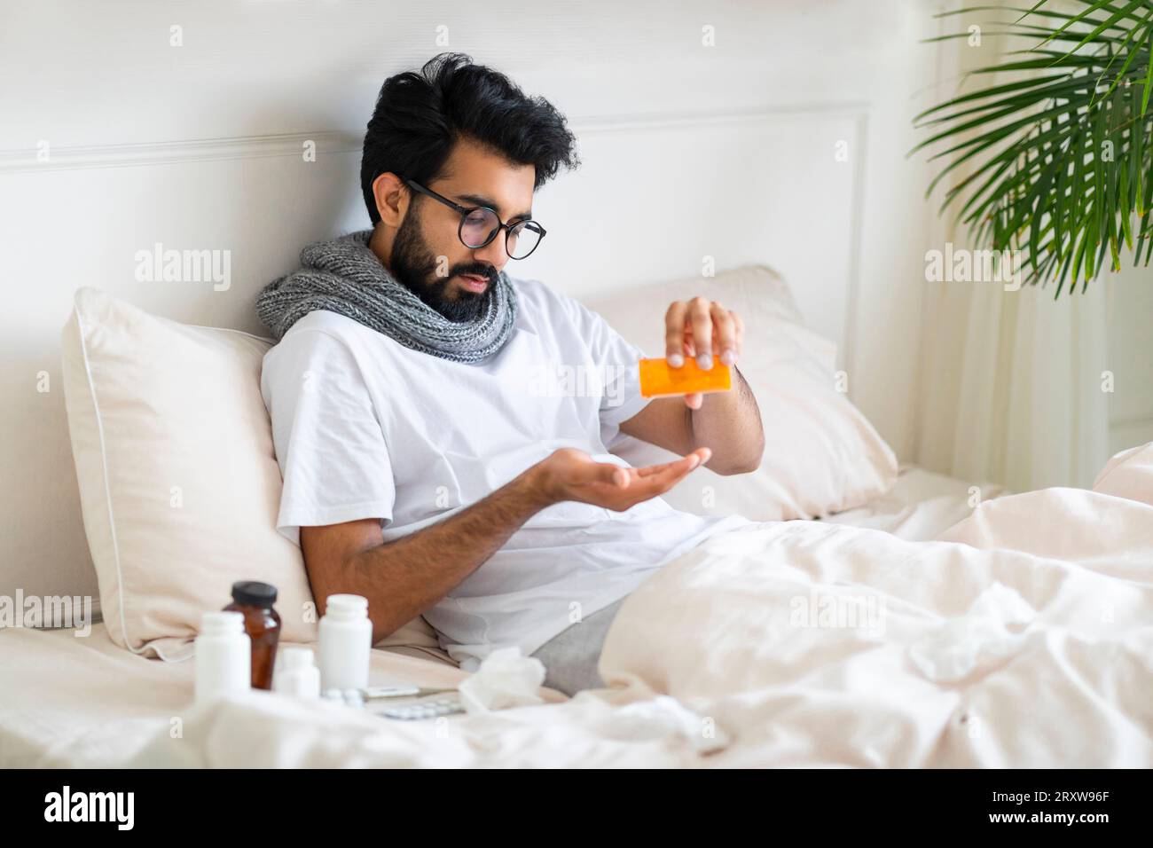 Sick Young Indian Man Taking Medicine While Sitting In Bed At Home ...