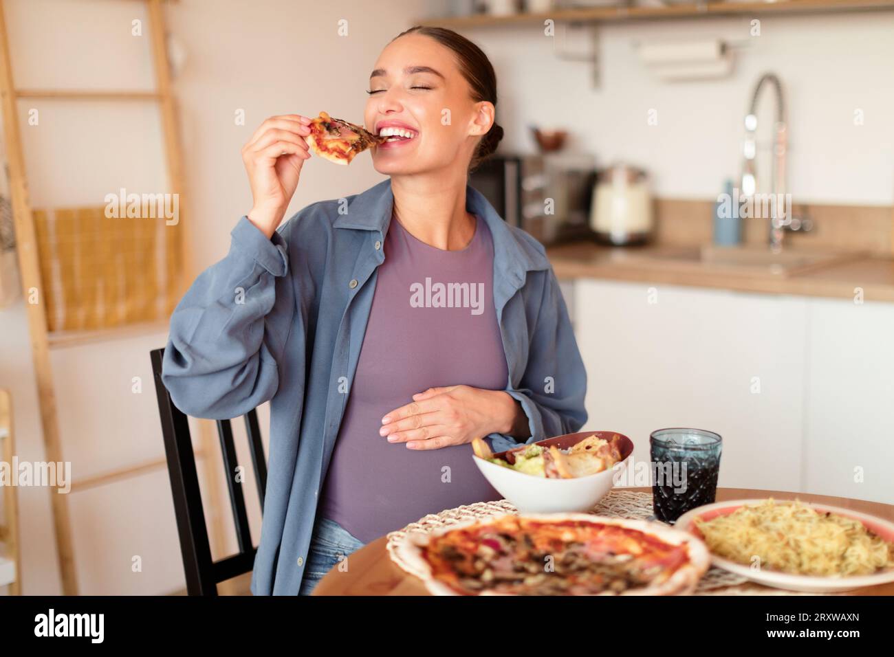 Young hungry pregnant woman biting slice of pizza, having desire for ...