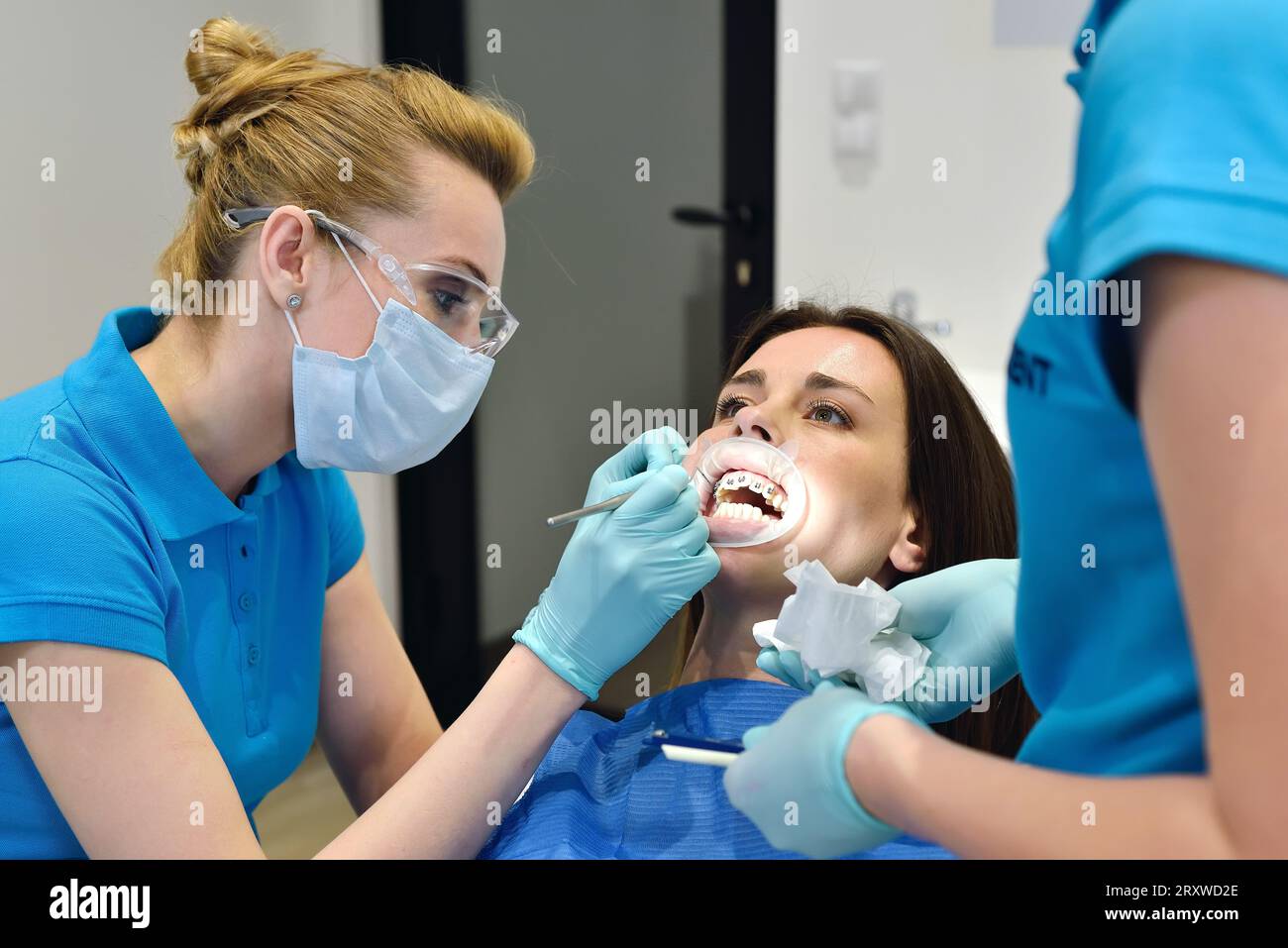 Dentist And Assistant Examine Patient With Braces In Dental Office ...