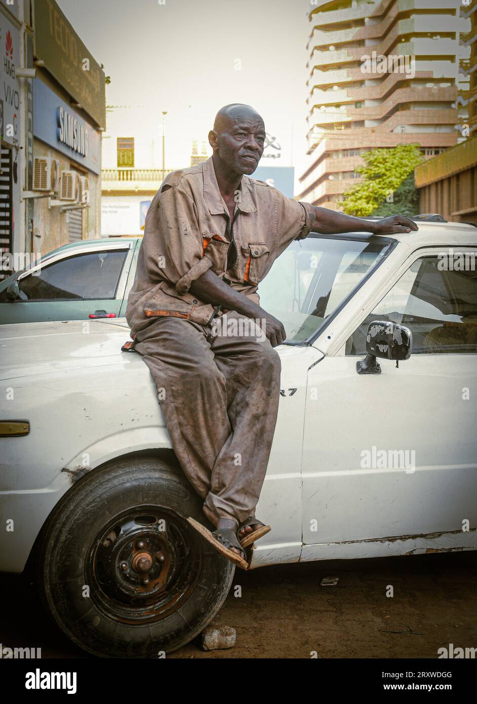 A picture of an African man working as a mechanic sitting on top of his ...