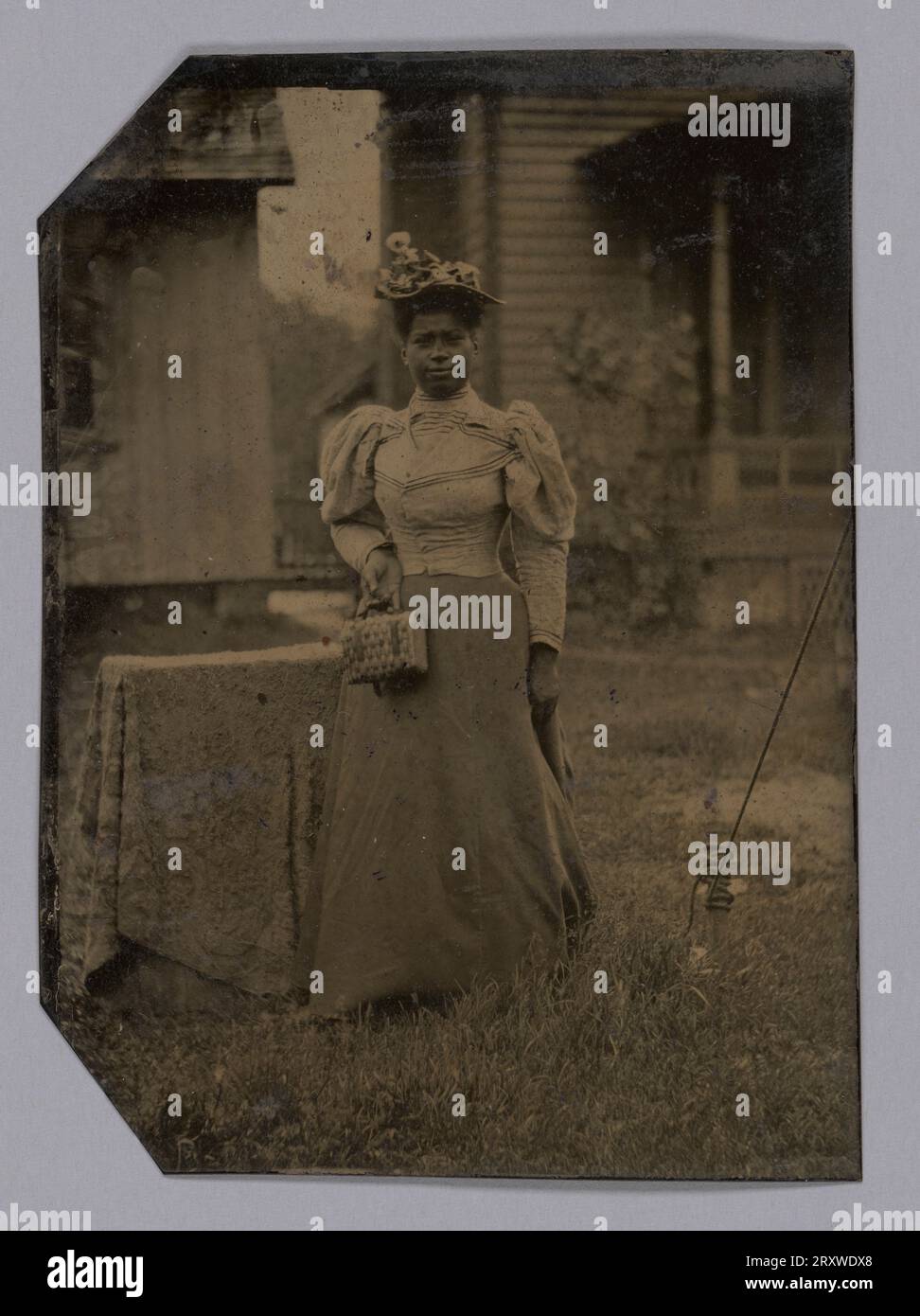 Tintype depicting woman who is standing outside in front of a house and ...