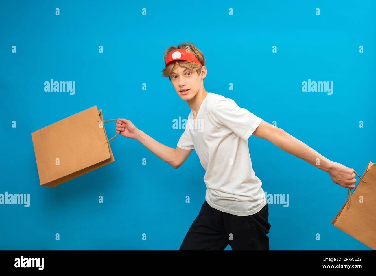 Harry up. Young seller in casual white t-shirt with paper bag running ...
