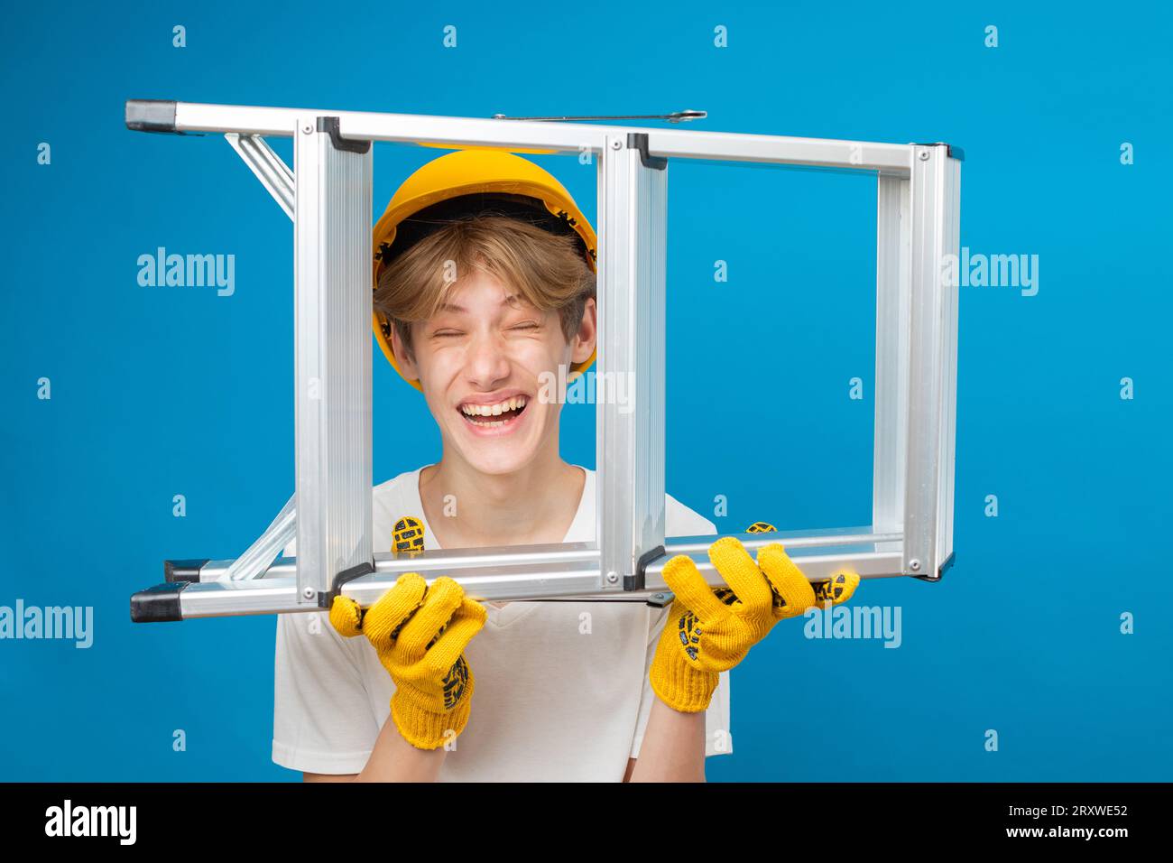 Happy repairman teen in white t-shirt and gloves with yellow helmet in ...