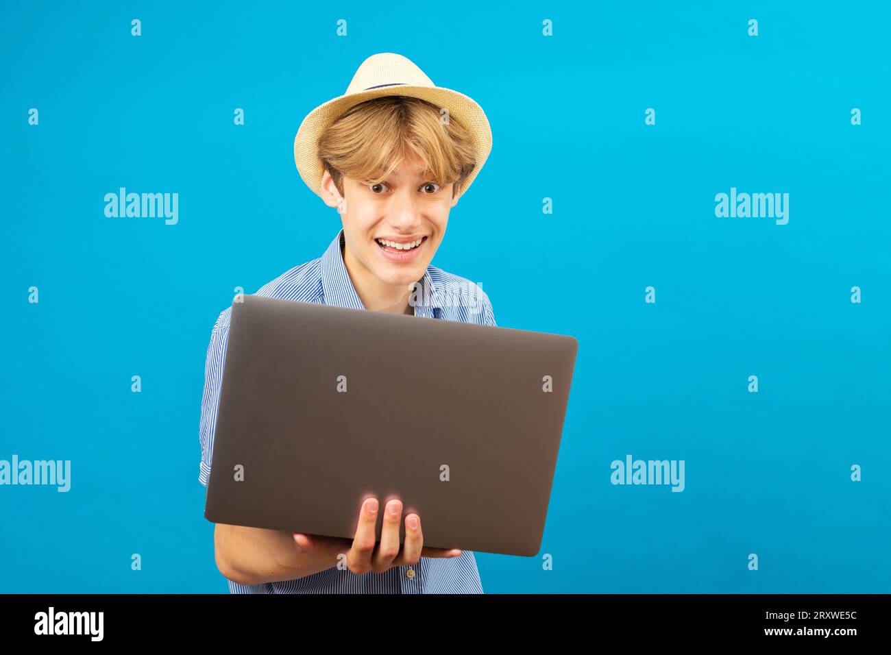 Smiling positive businessman teen holding laptop in hands and typing ...