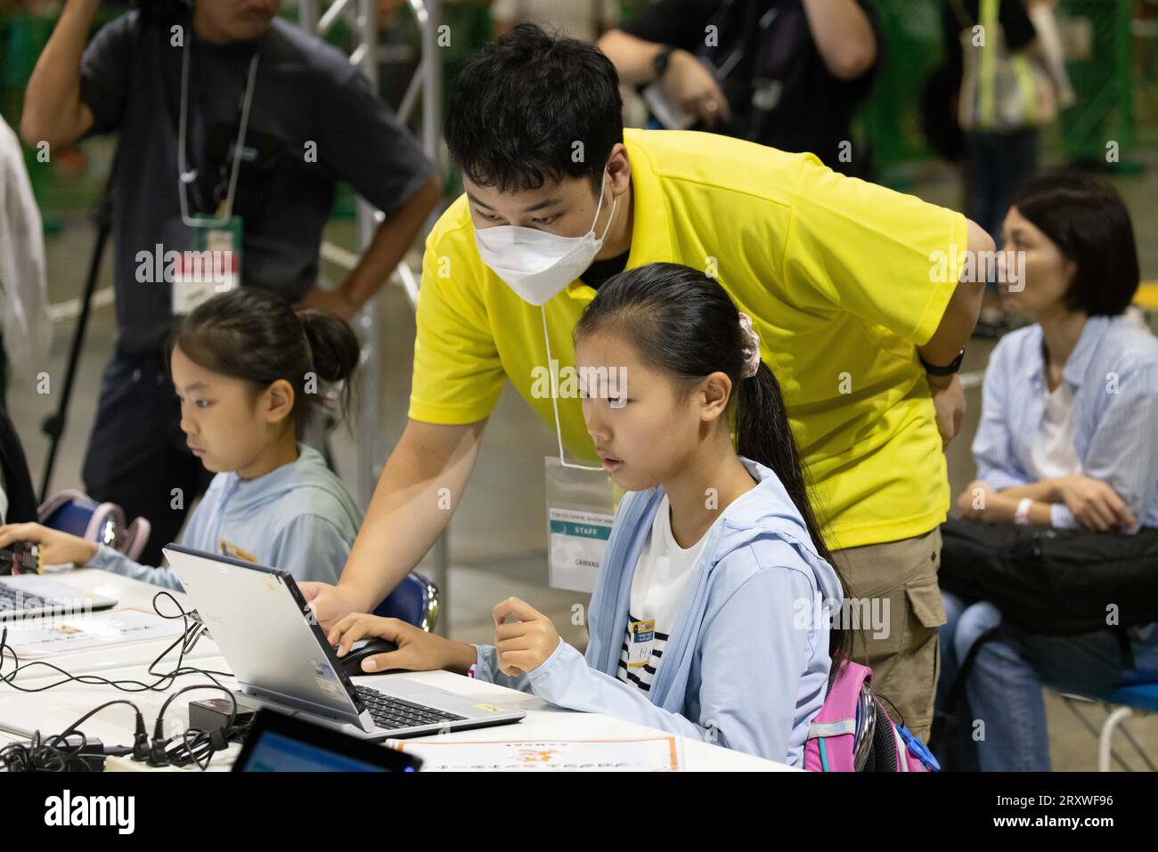 Participant of a video game programming workshop for kids receives help ...