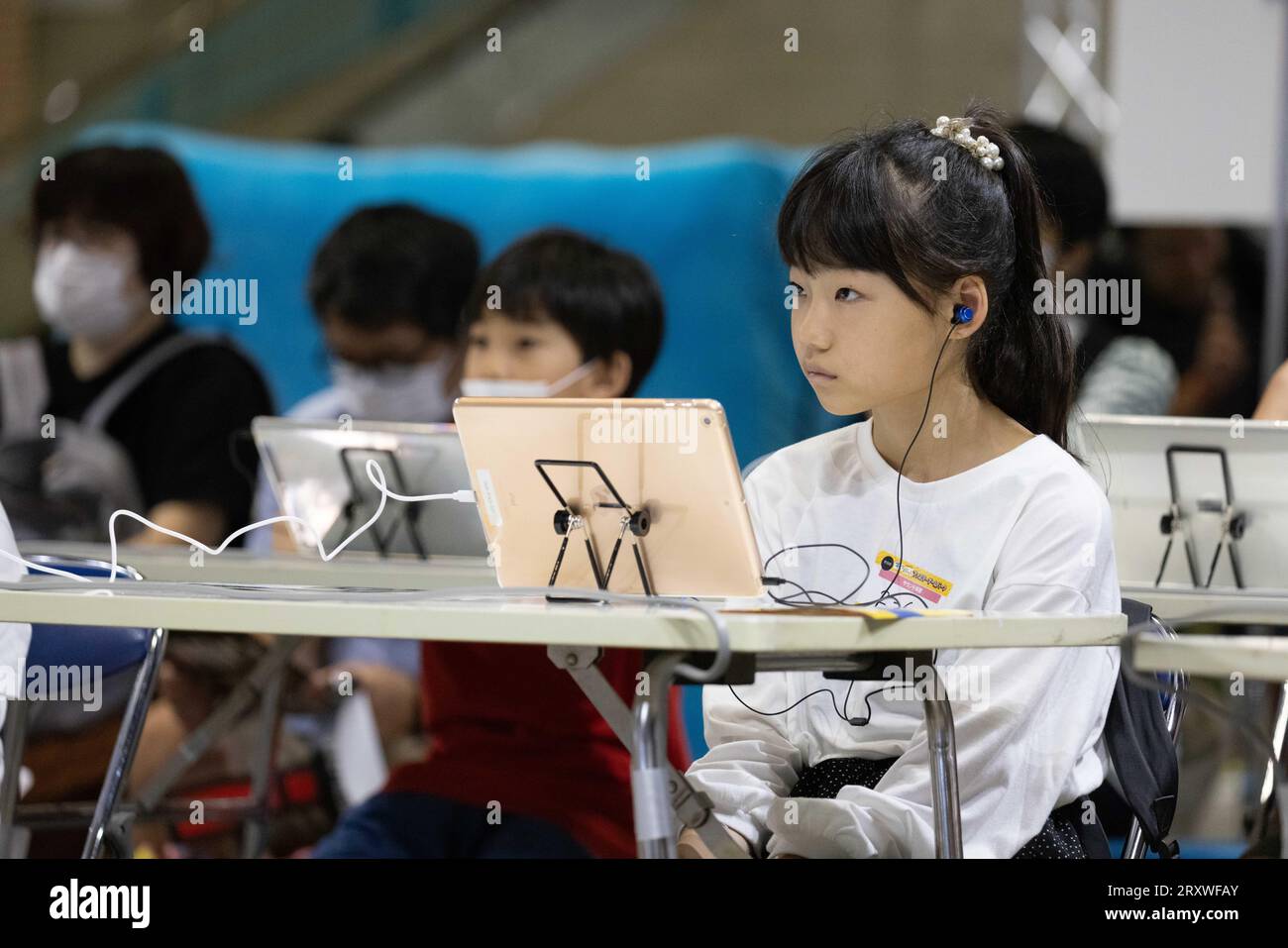 Participant of a video game programming workshop for kids listens to explanations of the ...
