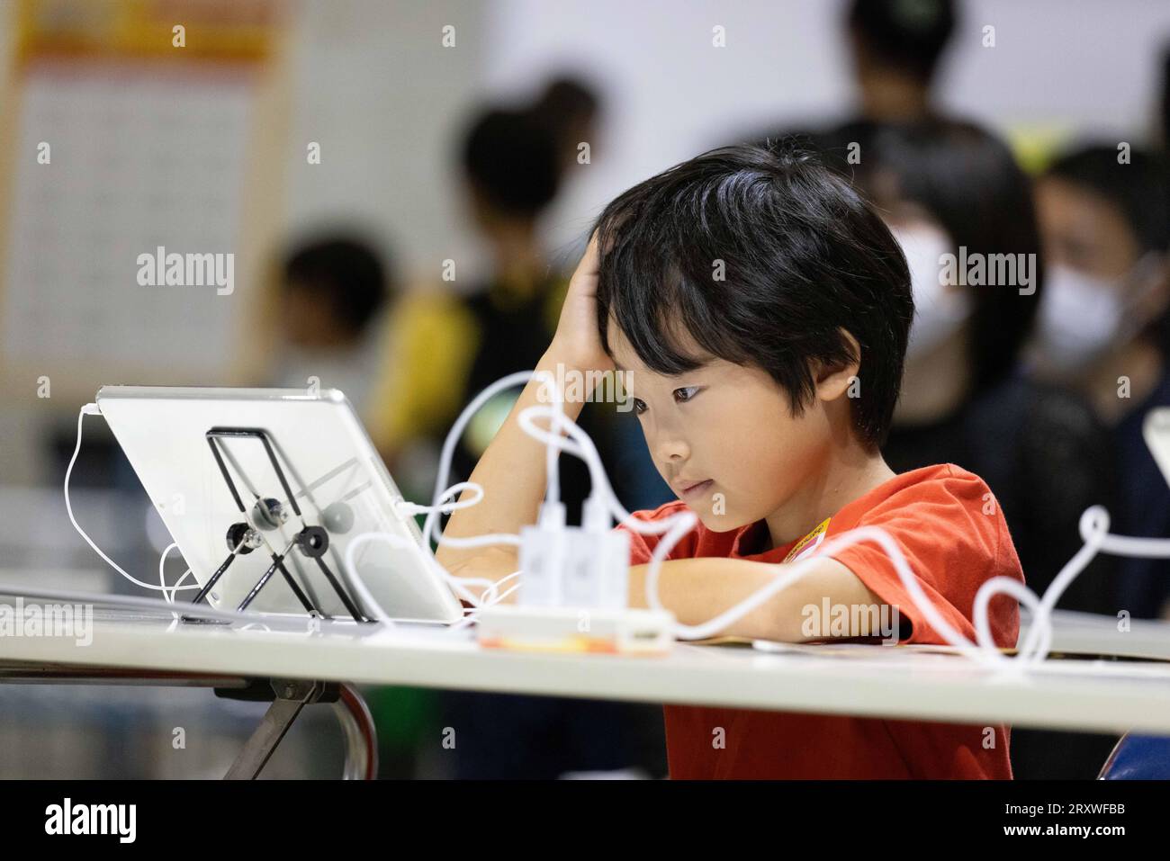 Participant of a video game programming workshop for kids thinks about an assigned programming ...