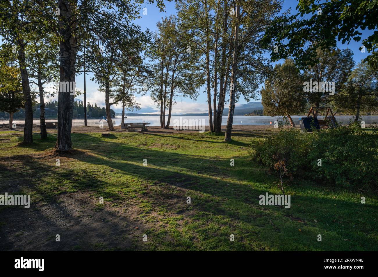 Trees shading the beach of Lake Windermere in the town of Invermere ...
