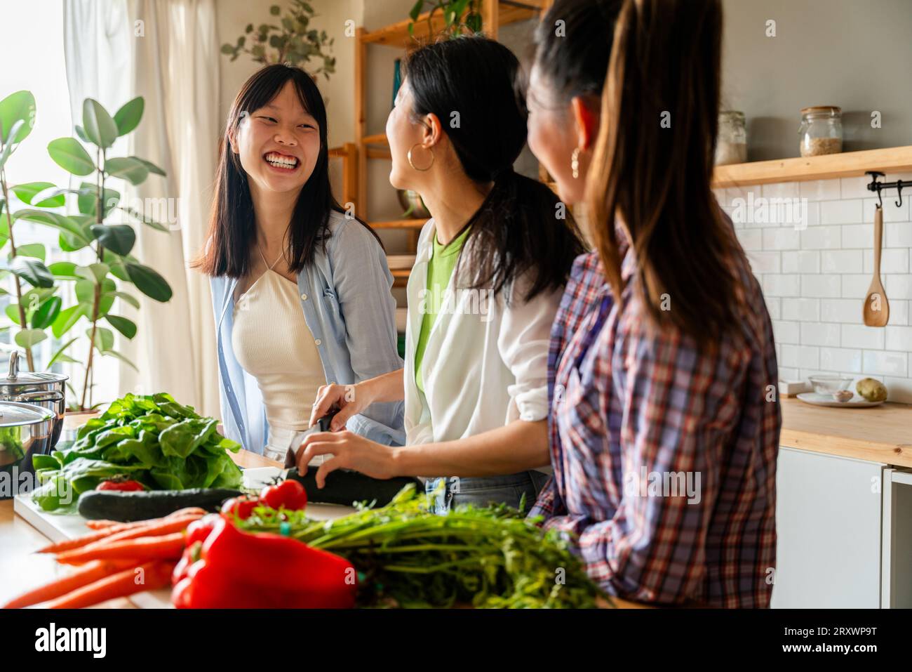 Happy beautiful chinese women friends bonding at home and cooking ...