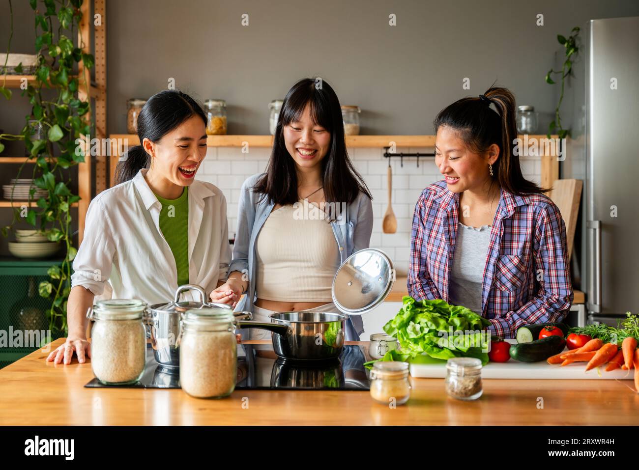 Happy beautiful chinese women friends bonding at home and cooking ...