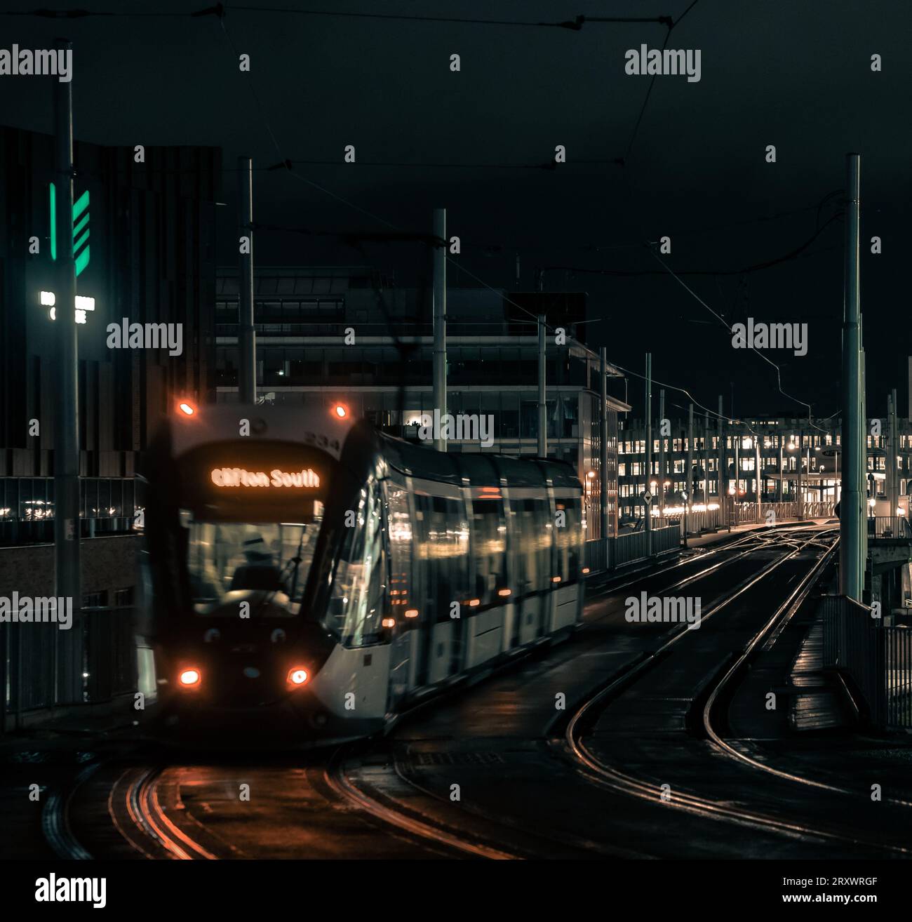 Blurred motion of trams travelling on rails in Nottingham City at night ...