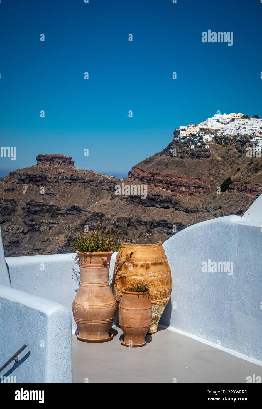 Santorini roof top, white wall, large clay Greek urns. View of blue sky ...