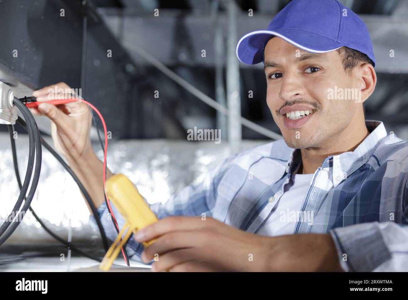 electrician using multimeter in roof space Stock Photo - Alamy