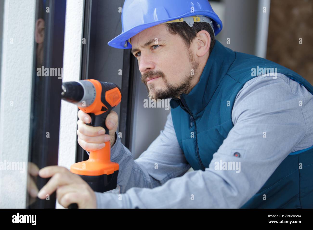 man drilling a hole in a window frame Stock Photo - Alamy
