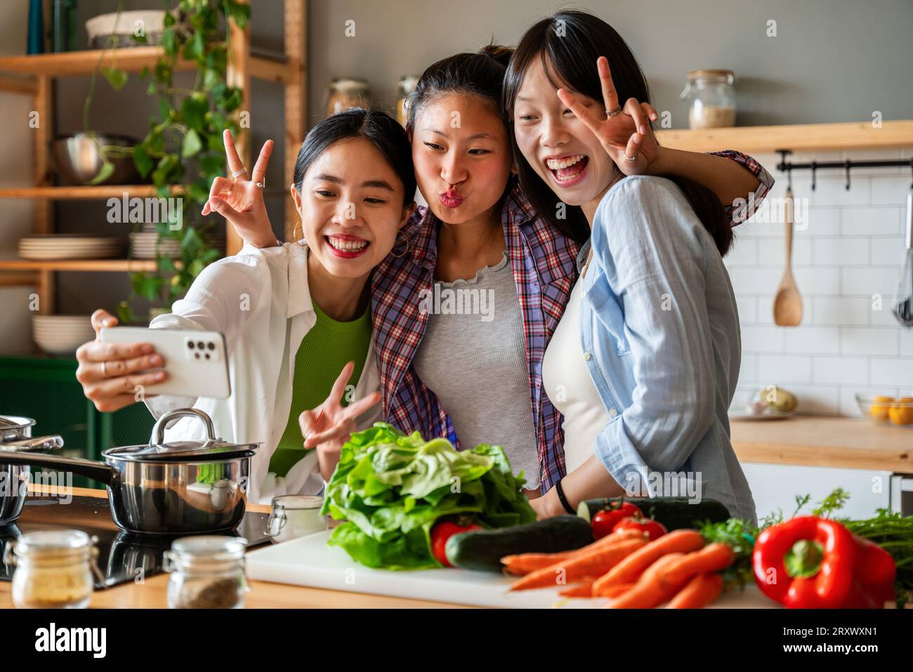 Happy beautiful chinese women friends bonding at home and cooking ...