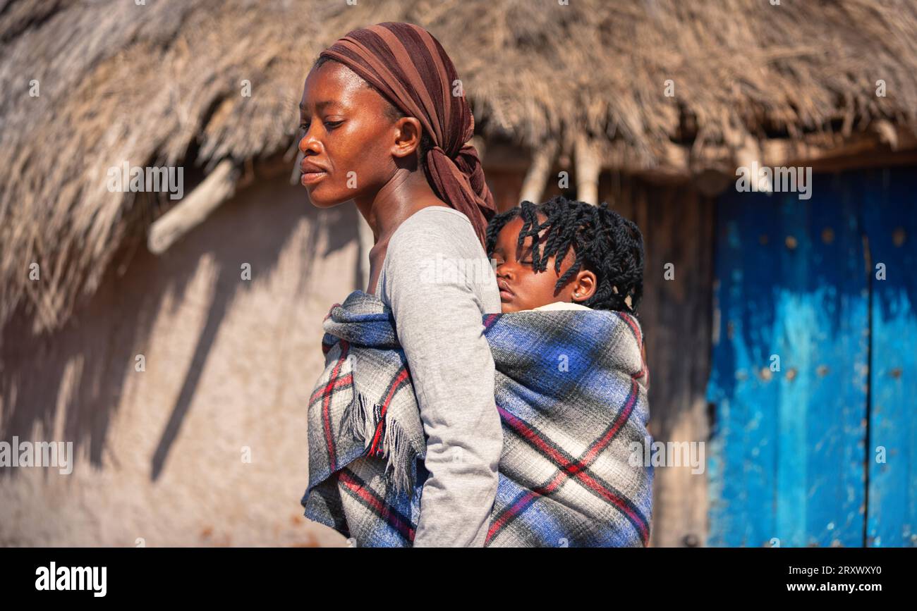 african mother in the village carry her child in the back in a ...