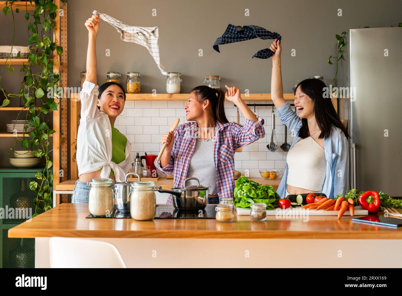 Happy beautiful chinese women friends bonding at home and cooking ...