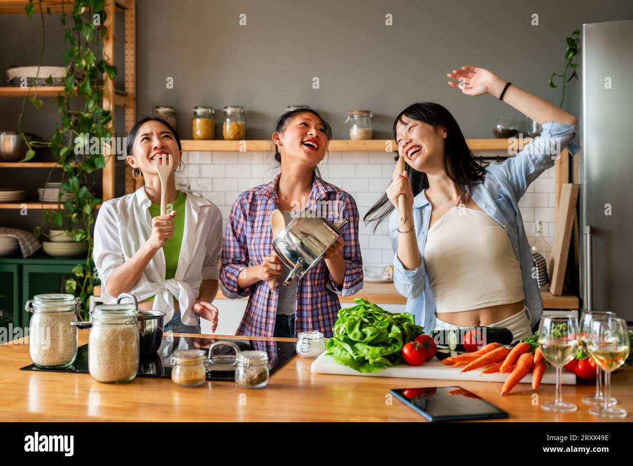 Happy beautiful chinese women friends bonding at home and cooking ...