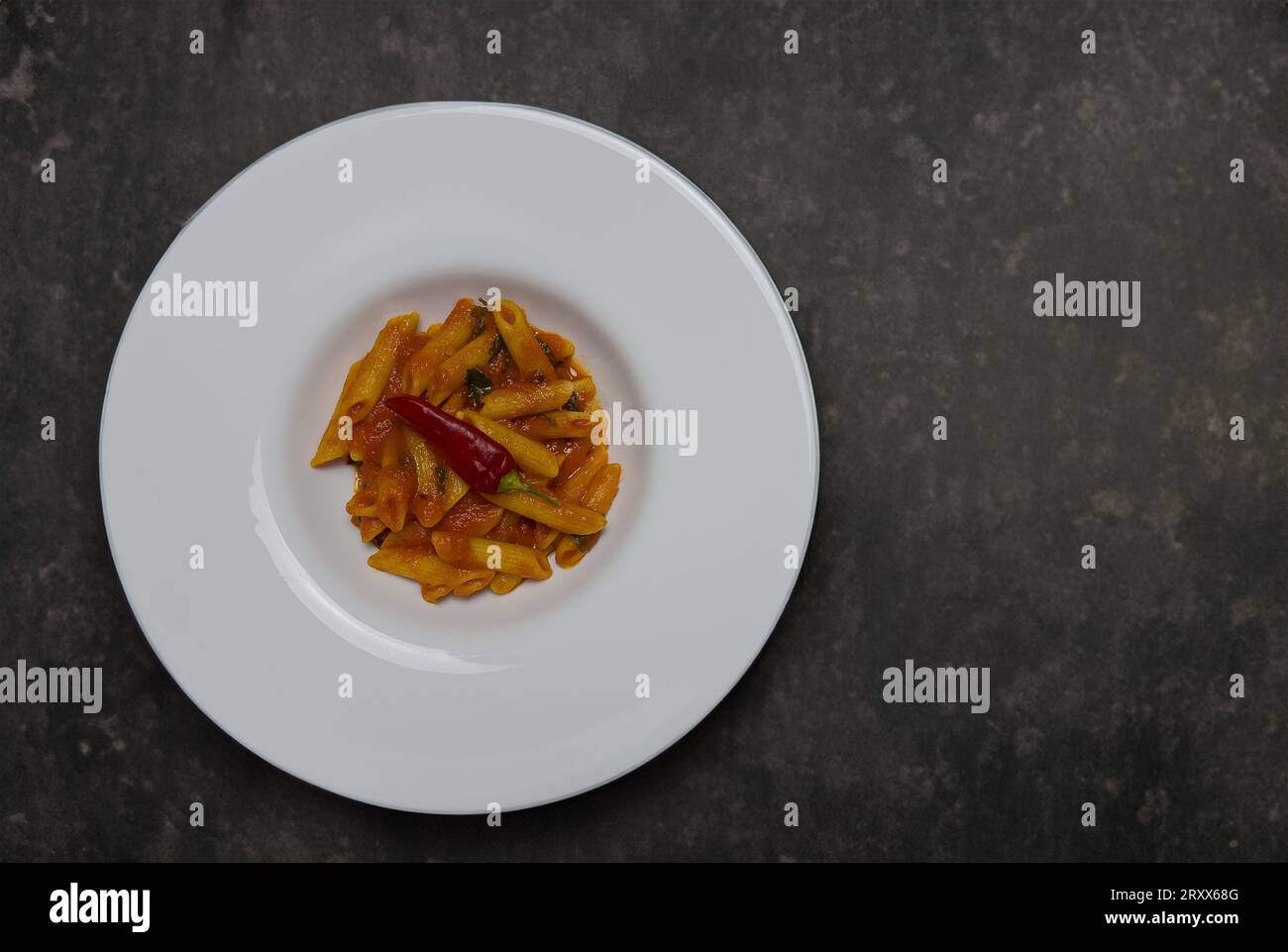 Classic Italian pasta penne arrabiata with chili peppers basil on dark ...