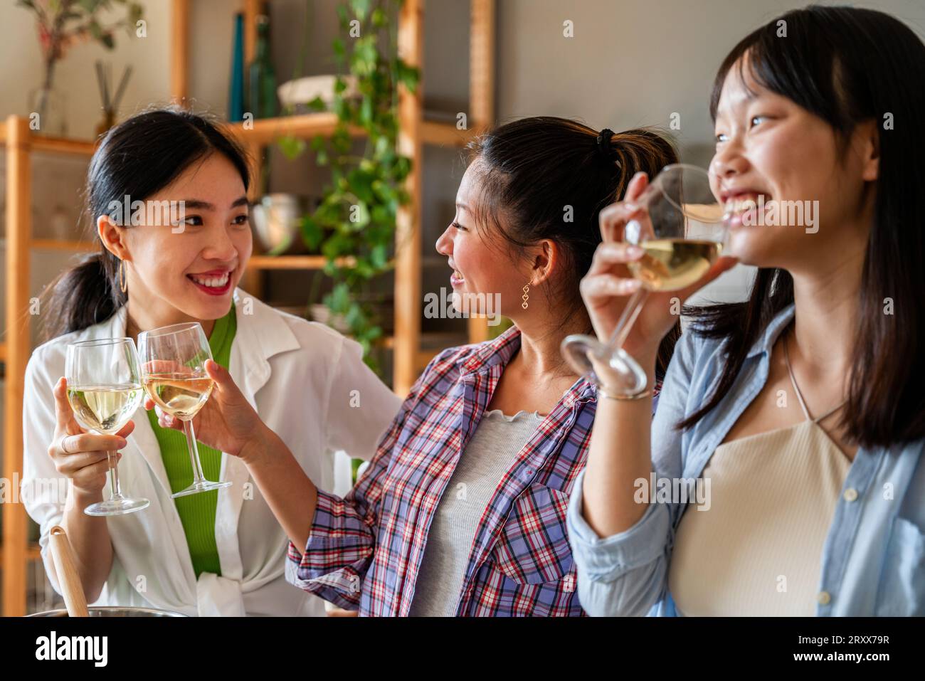 Happy beautiful chinese women friends bonding at home and celebrating drinking wine- Playful ...