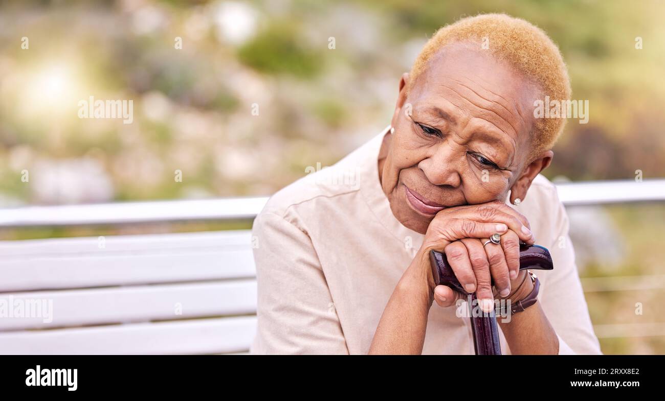 Depression, walking stick and a sad senior woman on a park bench with ...