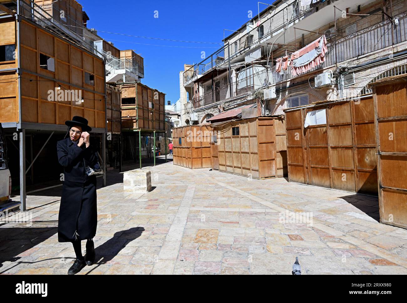 An Ultra-Orthodox Jew walks past wooden temporary huts, sukkahs, used ...