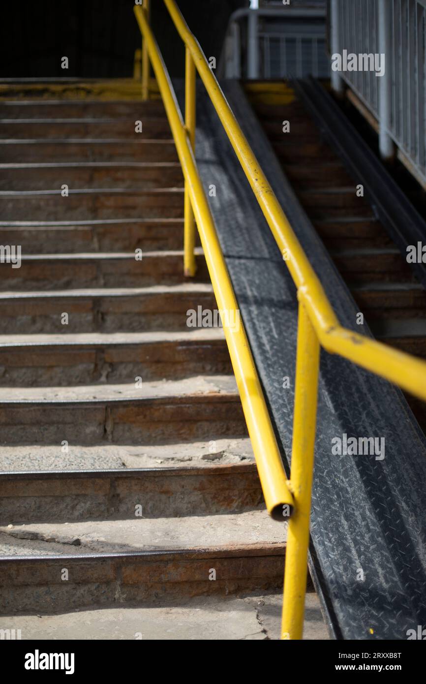 Steep stairs. Yellow handrail for climbing stairs. Overhead road ...