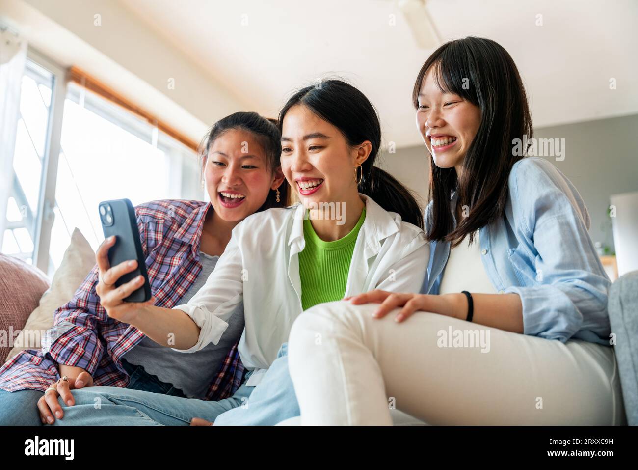 Happy beautiful chinese women friends bonding at home - Playful pretty ...