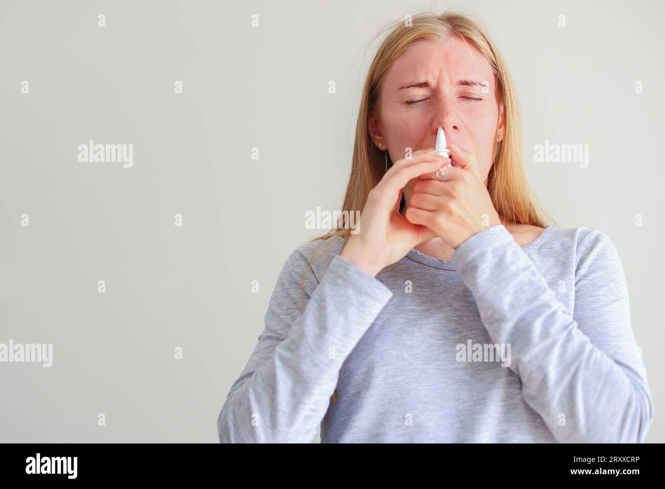 a woman is sick with a real flu and sprays spray into her nose for a ...