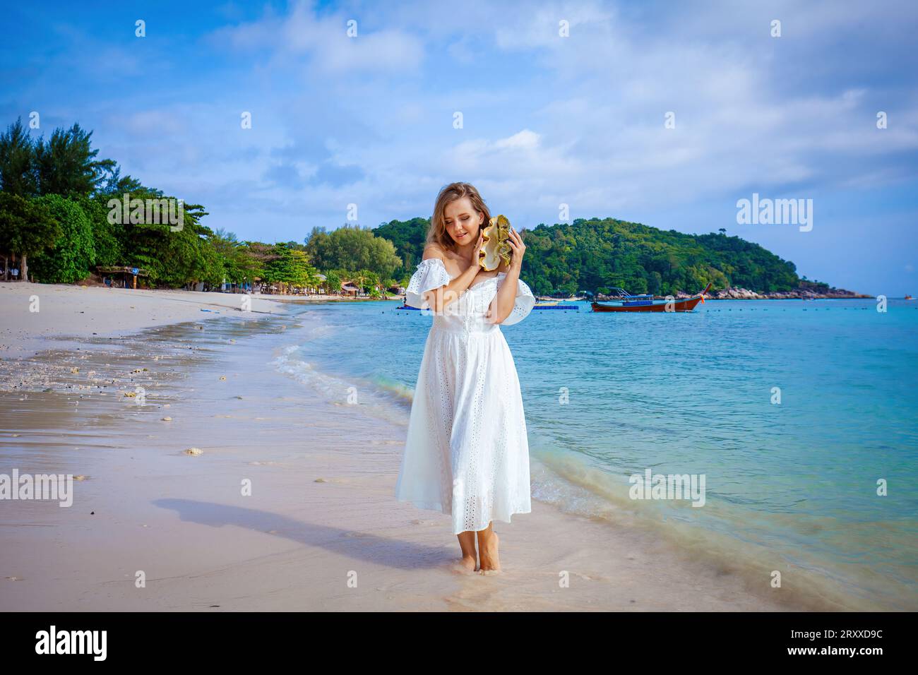Woman in white dress holds seashell, enjoys the ocean view Stock Photo ...
