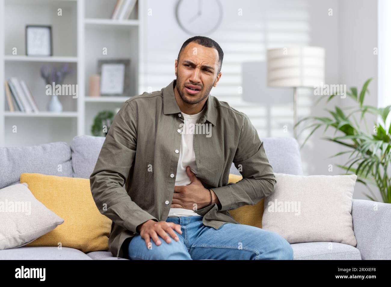 A young African American man is suffering from abdominal pain, stomach ...